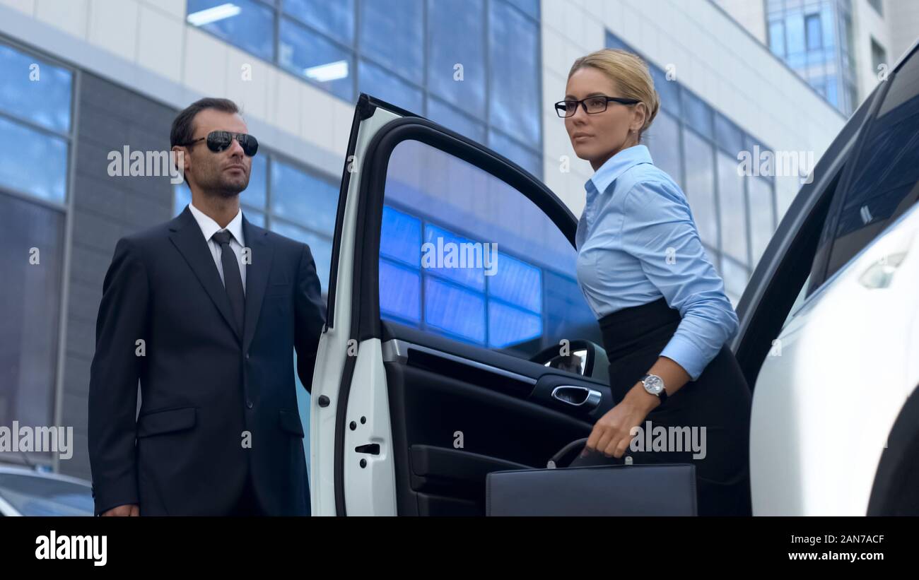 Bodyguard in suit opening car door to female boss, luxury service ...