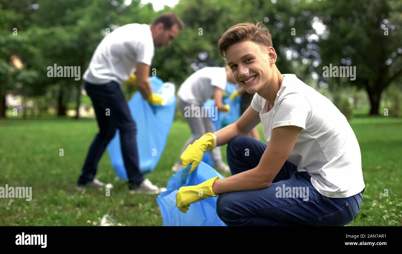 Volunteers collect litter, teenager smiling, environmental and ...
