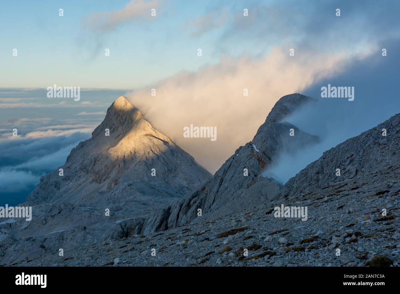 Spectacular mountain view with evening clouds rolling over peaks and ...