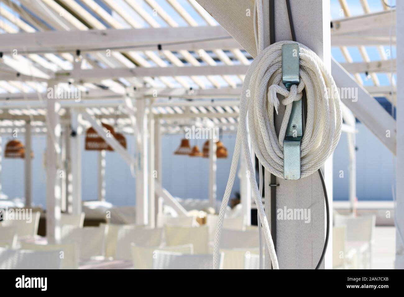 A white rope hung on the pillars of a beach terrace unified in solid ...