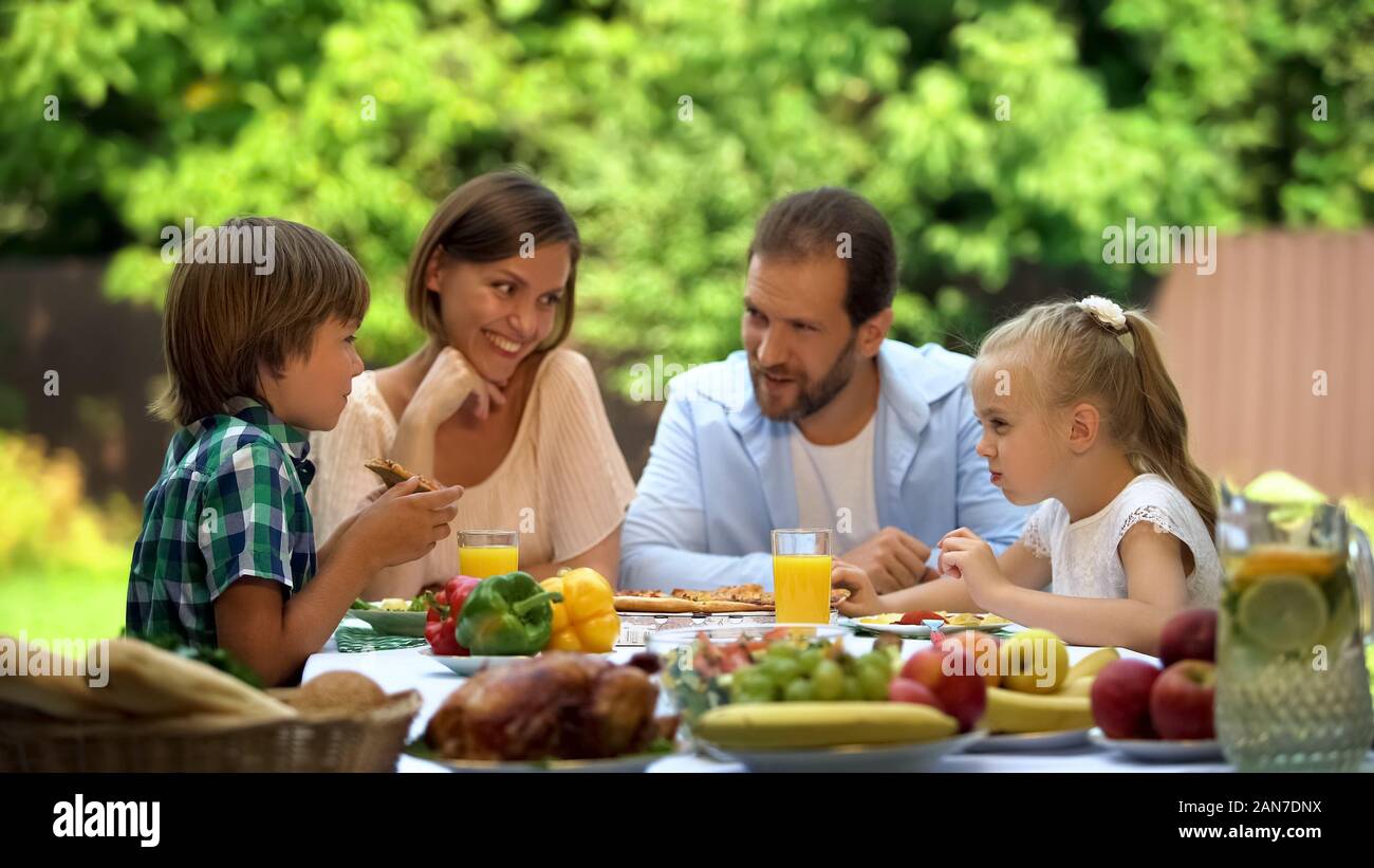 Friendly family having traditional dinner outdoors, parents kids happy ...