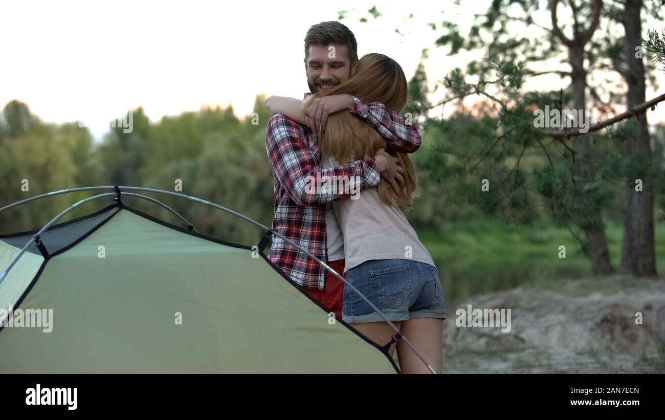 Couple embracing, putting up tent, great teamwork, wilderness survival ...
