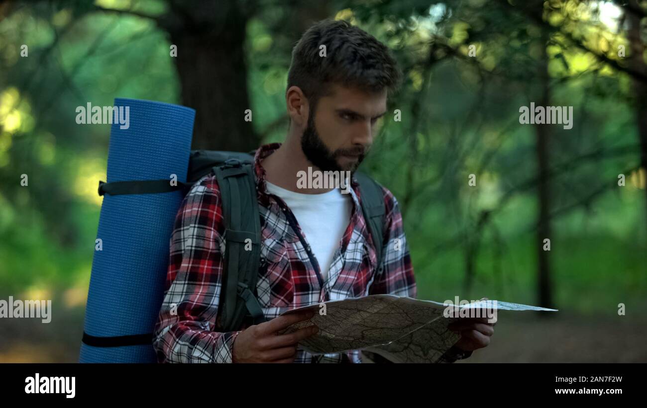 Confused camper orienteering with map in forest, searching for right ...