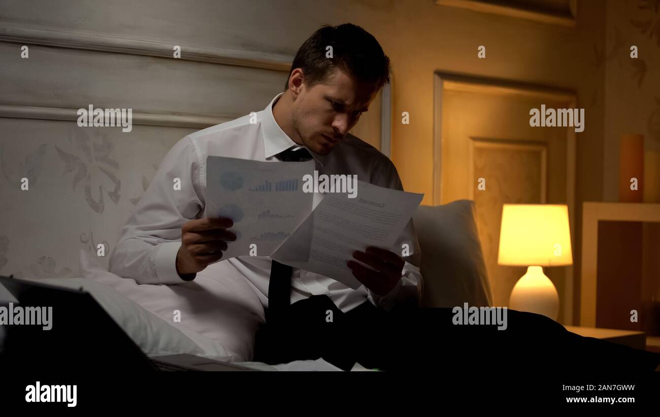 Male clerk preparing report late at night, comparing income of company ...