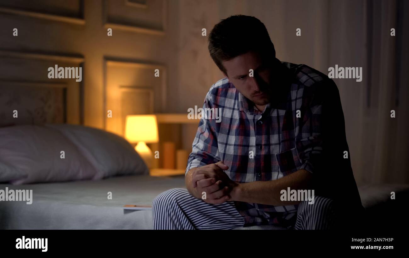 Lonely sad man sitting on bed, experiencing painful wife loss, grief ...