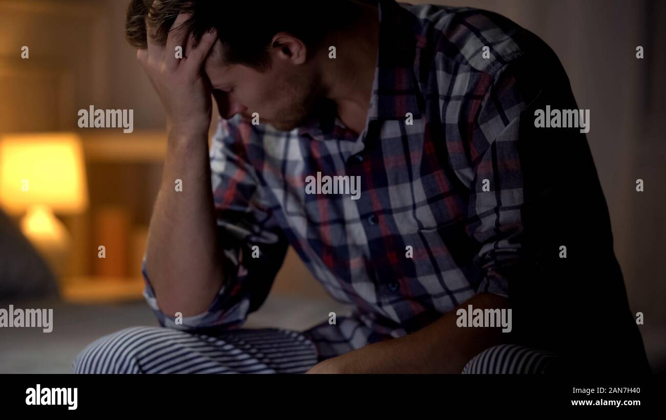 Sad man crying, sitting on bed, relative loss, lack of support, grief ...