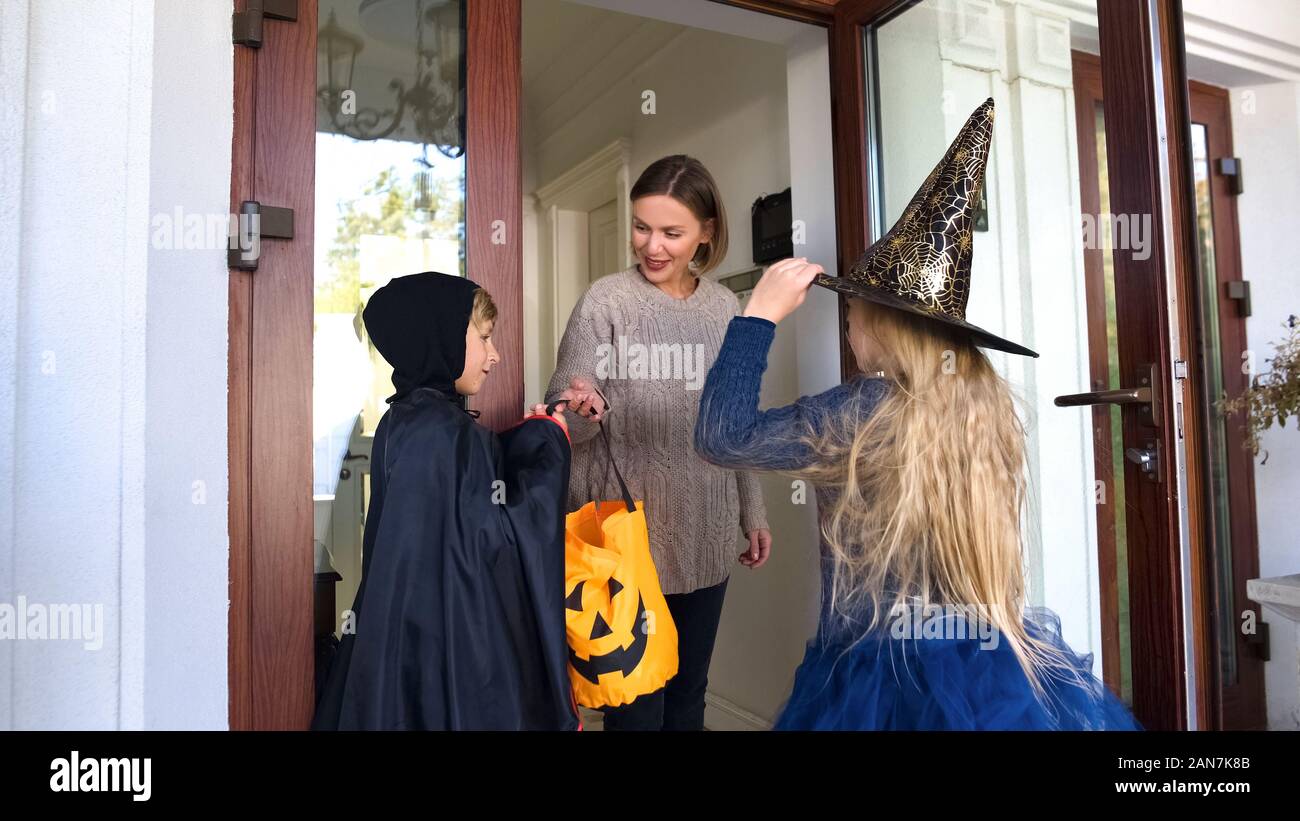 Mother dressing up children on trick-or-treating walk Halloween holiday ...