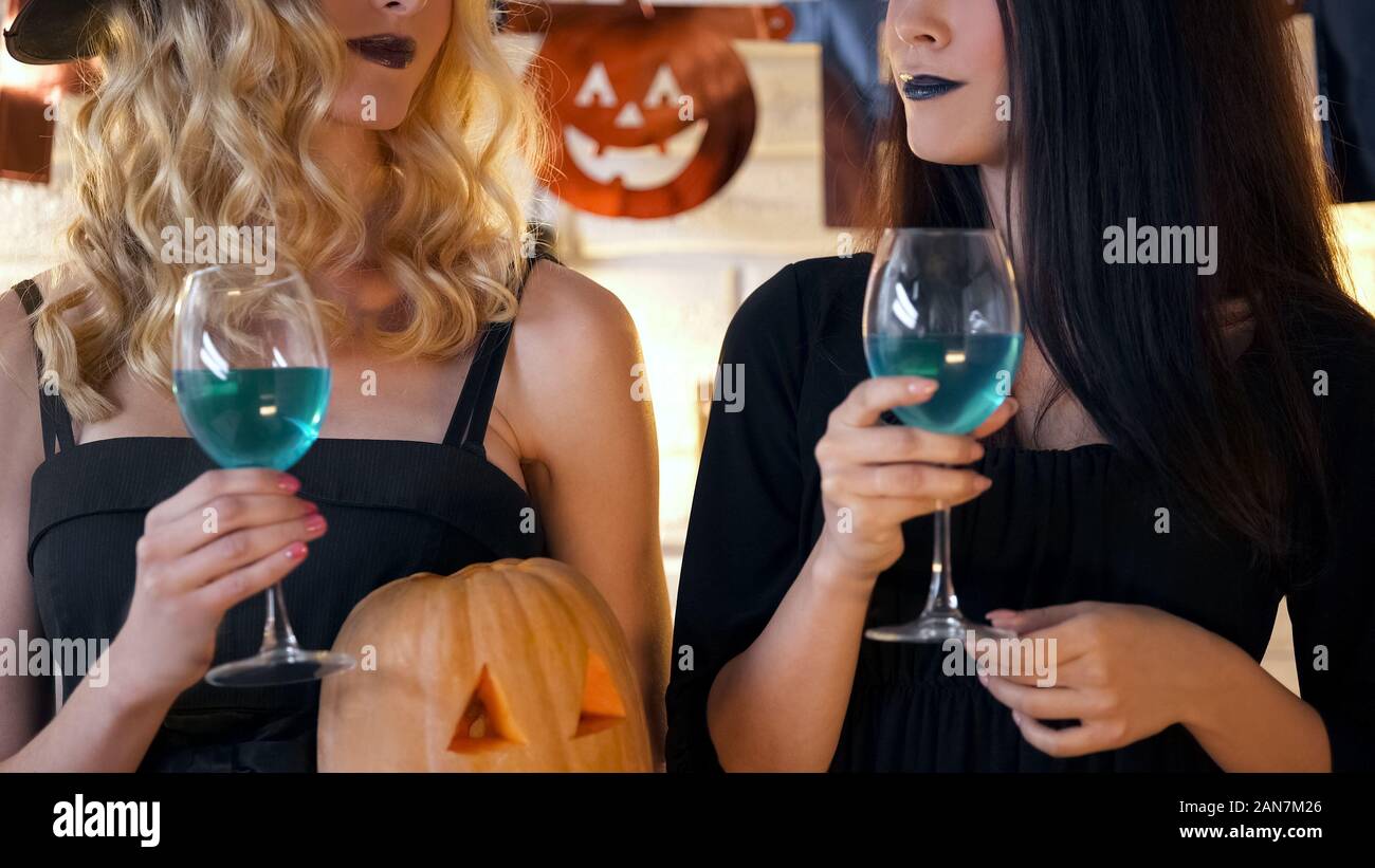 Witches holding cocktails and having fun at Halloween party, creepy ...