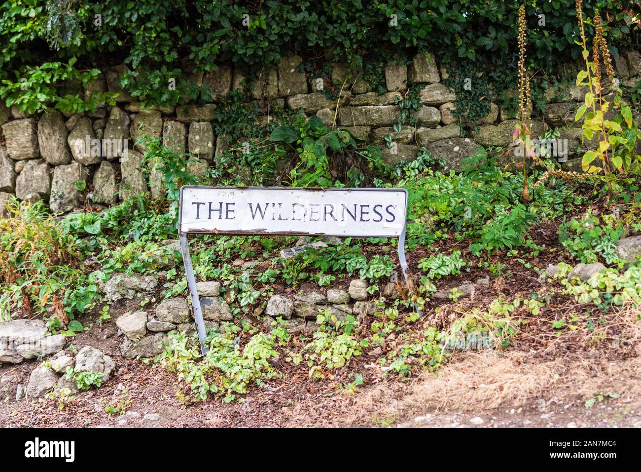 An old twisted and worn road name sign for "The Wilderness" in front of ...