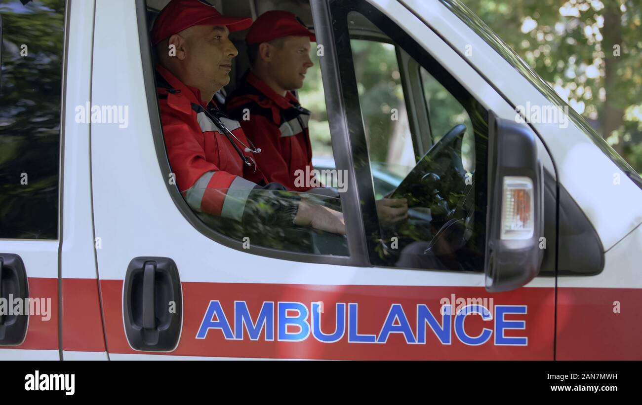 Male doctors sitting in ambulance, ready to drive out on call ...