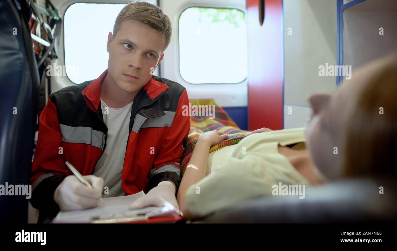 Doctor asking patient questions and filling out medical form in ...