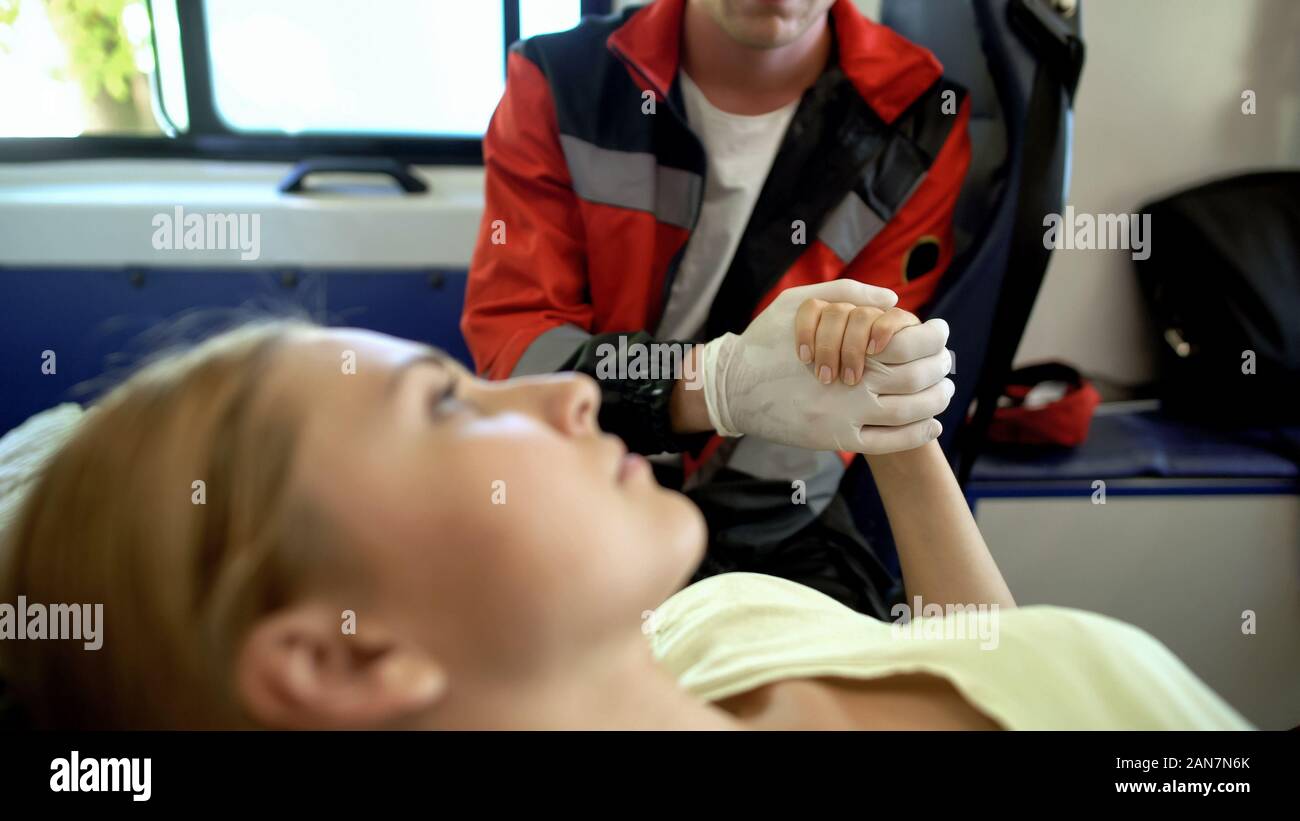 Emergency doctor holding patient hand in ambulance, medical care, moral ...