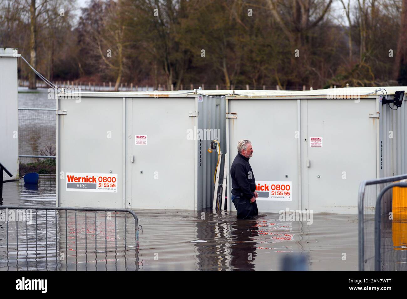 A worker uses waders as a construction site sits in flood water near ...