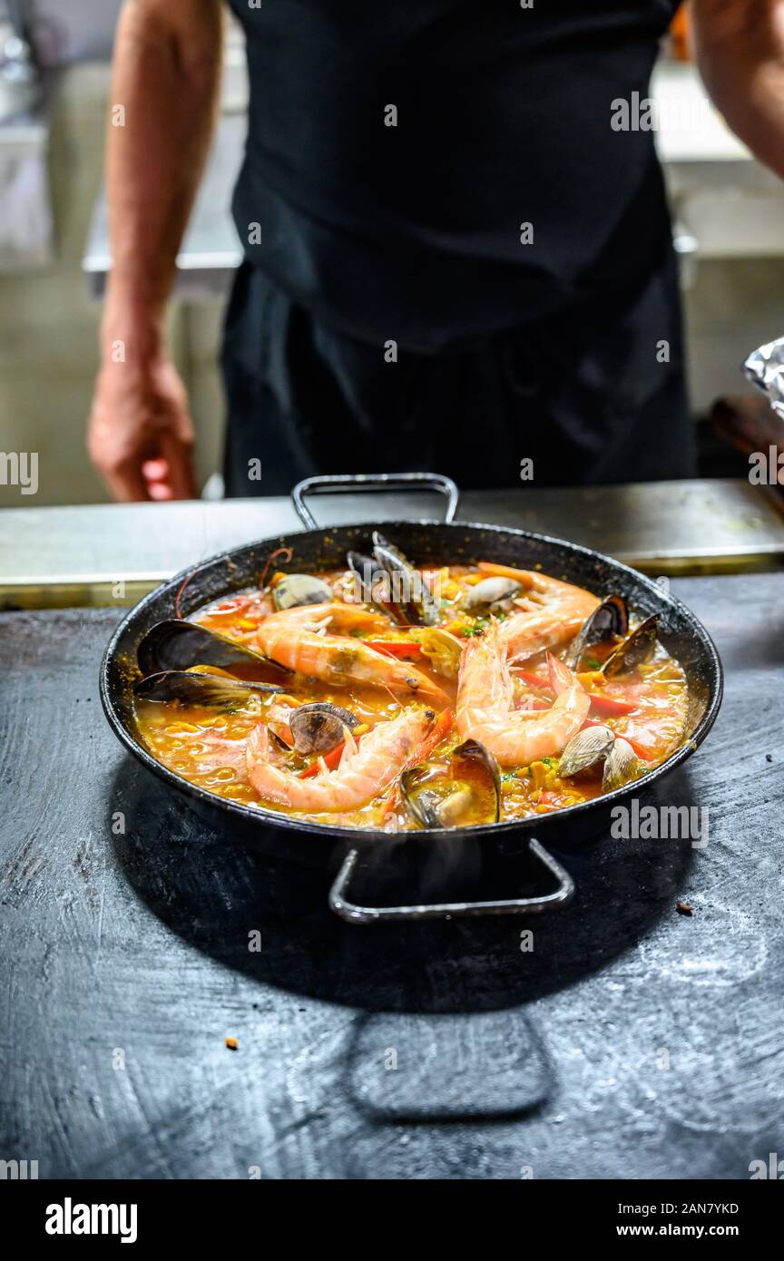Spanish cuisine, cook making tasty paella, famous dish with rice and ...