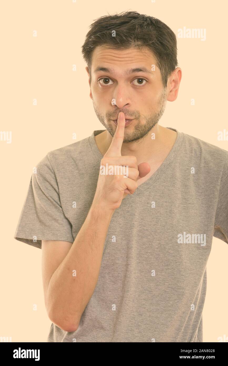 Studio shot of young man with finger on lips Stock Photo - Alamy