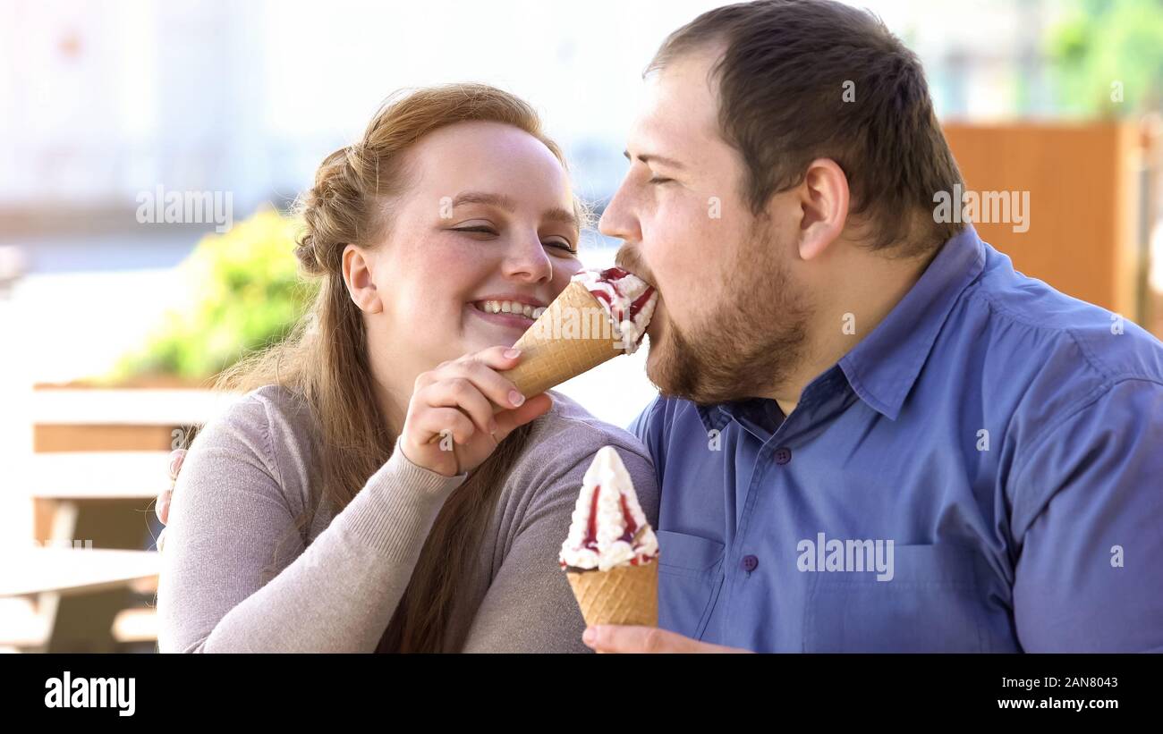 Fat boyfriend and girlfriend enjoying ice-cream dessert, overeating ...