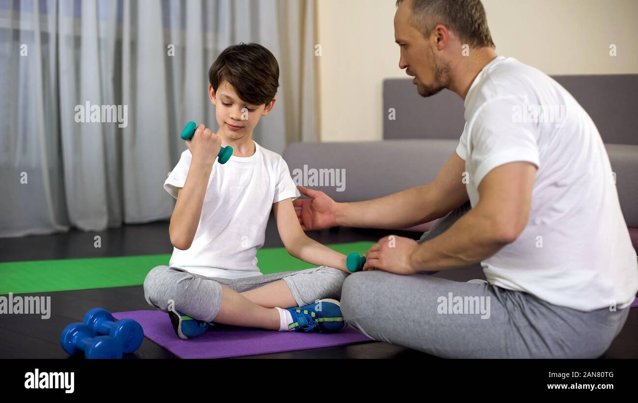 Father teaching son to make dumbbells exercise at home, active ...