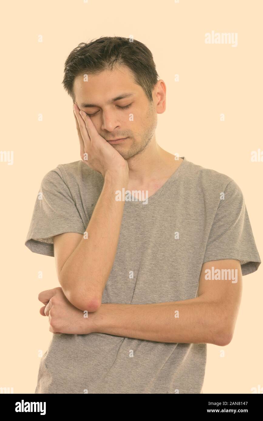 Studio shot of tired young man sleeping while resting face on hand ...
