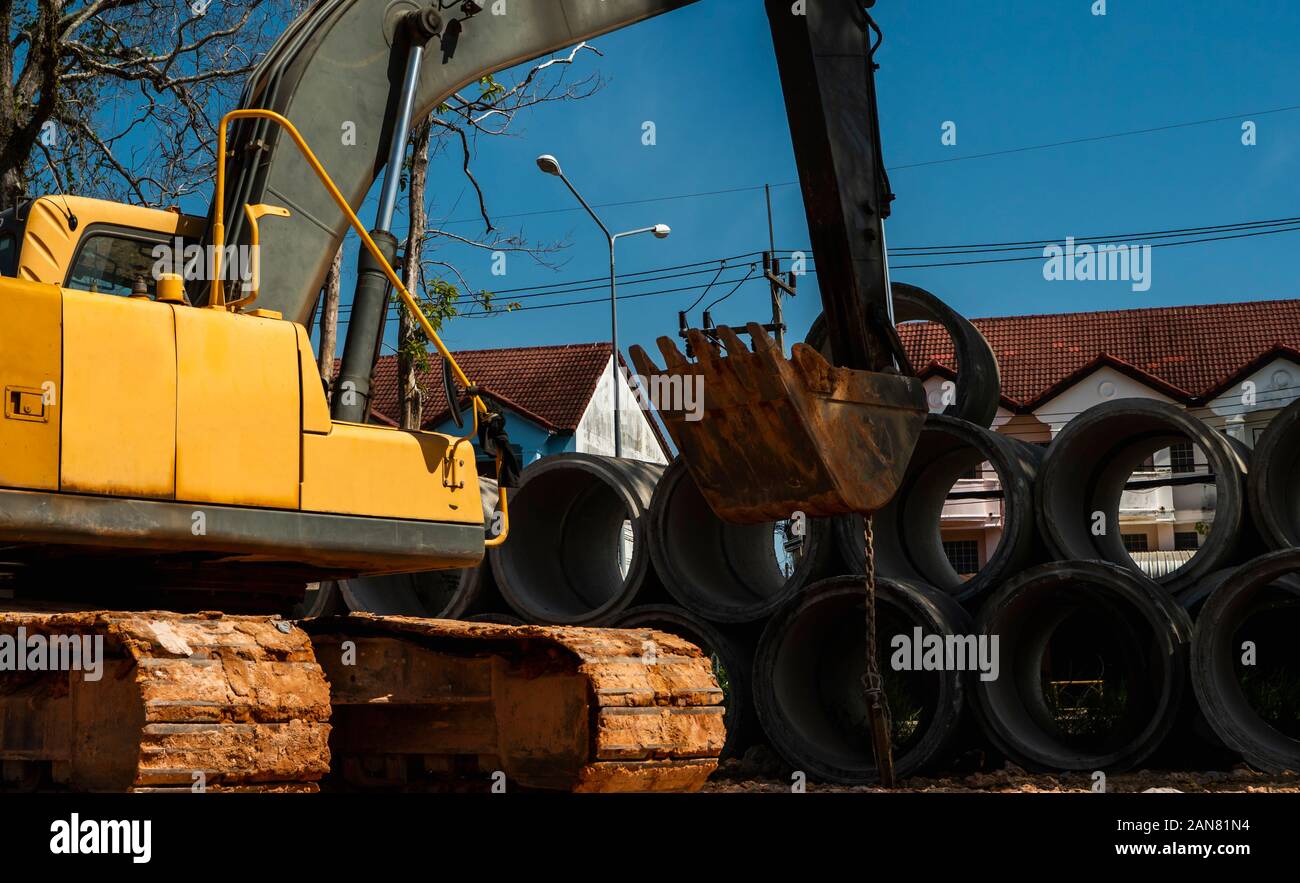 Using an excavator to transfer large pipes to a vehicle Stock Photo - Alamy