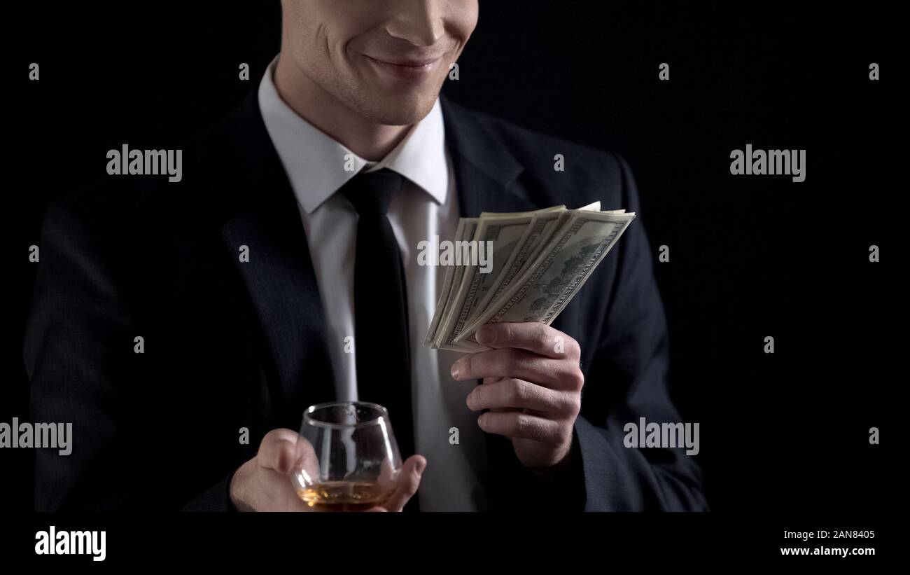 Businessman holding dollar cash and drinking cognac, celebrates income ...