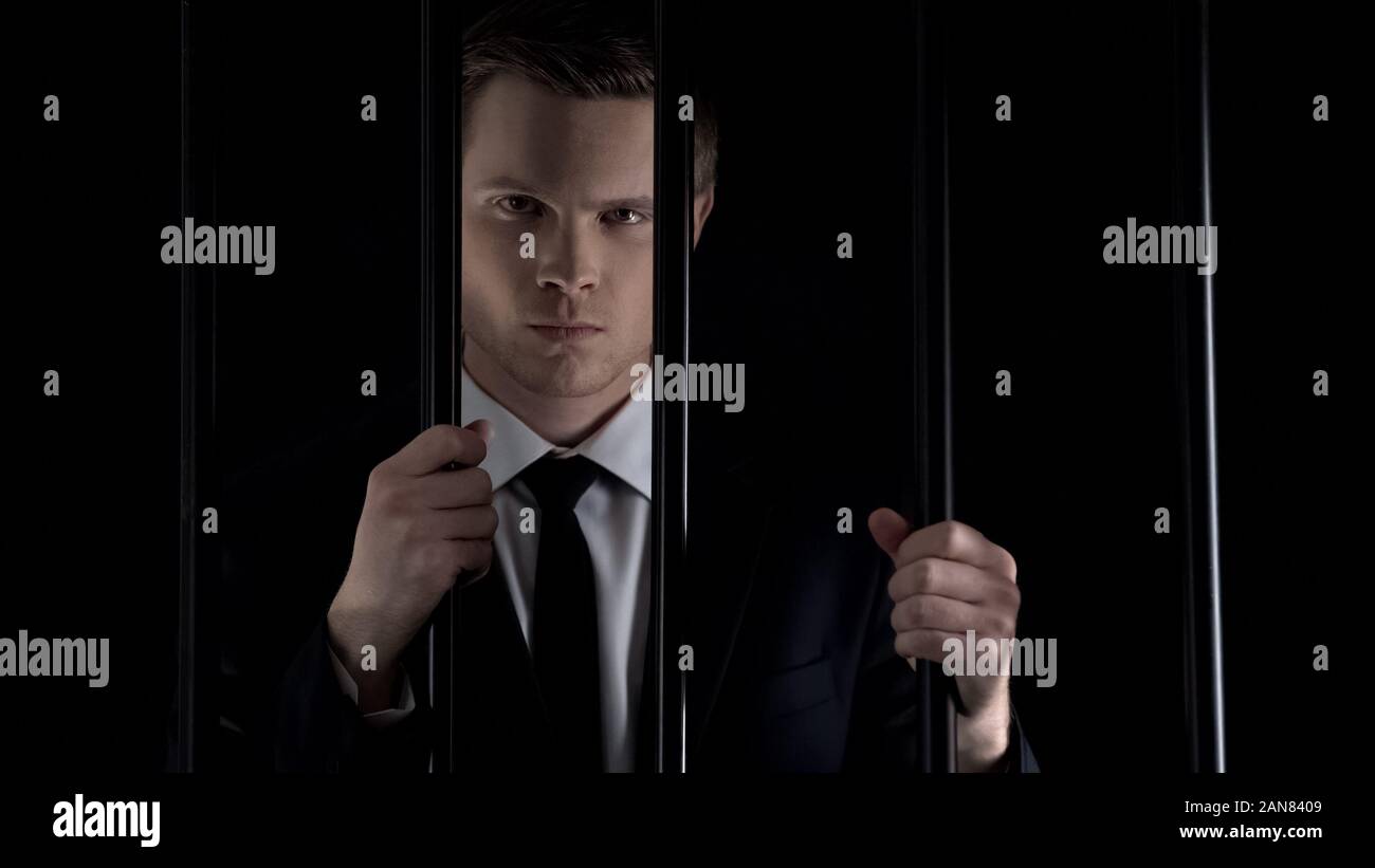 Angry man standing behind prison bars, official arrested on bribery ...