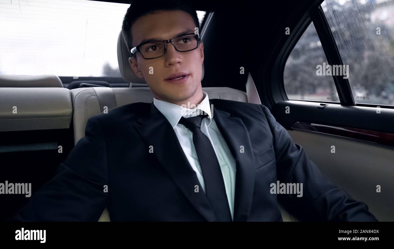 Worried businessman sitting on backseat of luxury car, late for work ...