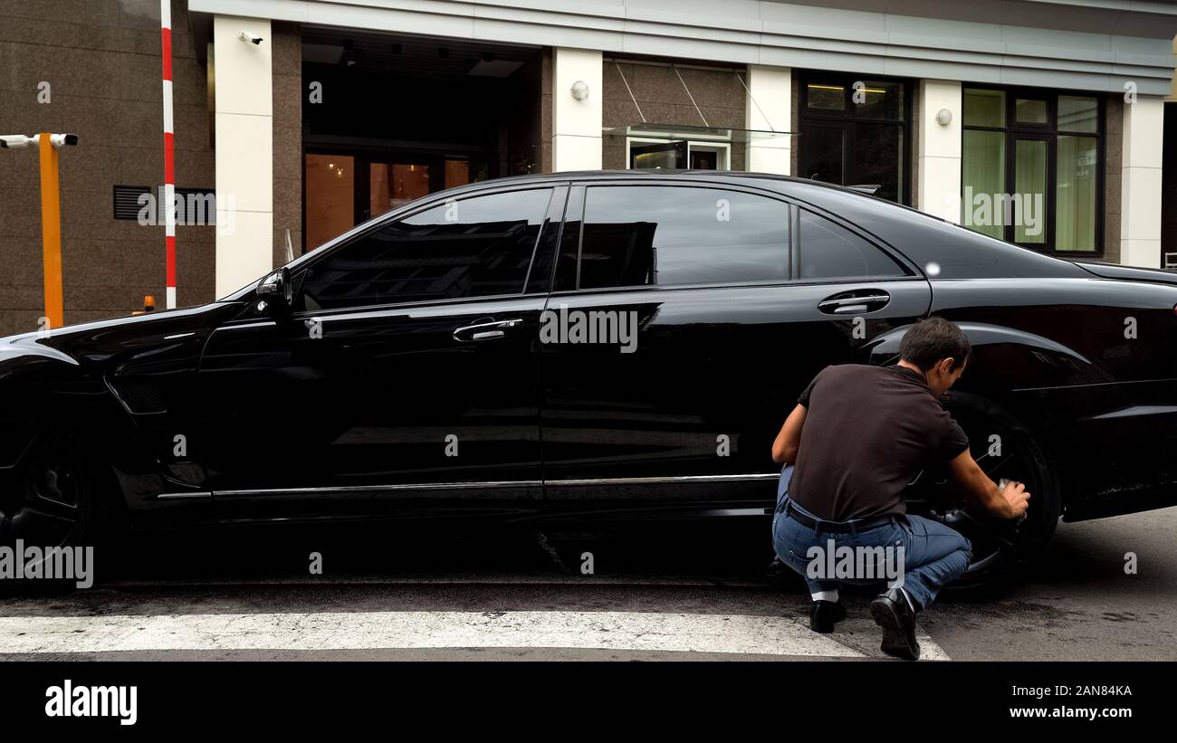 Male washing luxurious car near business center, labor migration ...
