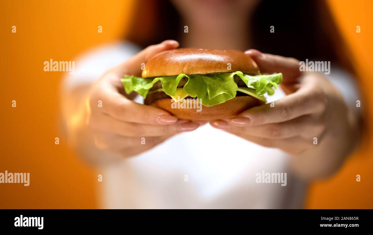 Woman showing beef burger to camera, temptation by fast food, unhealthy ...