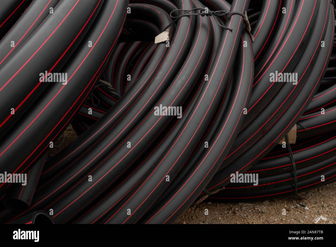 Black rubber or plastic pipes with a red lines as a construction ...