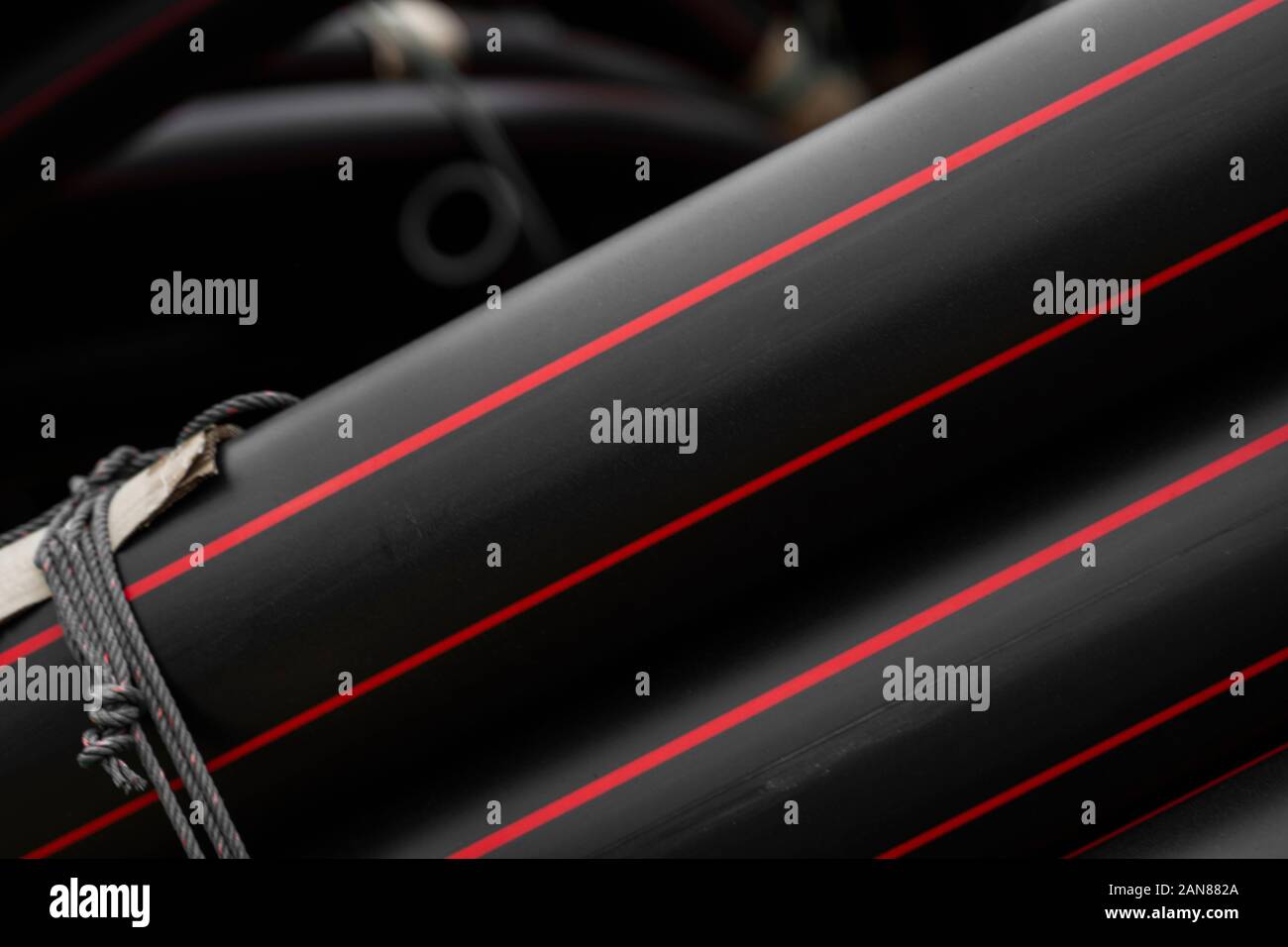 Black rubber or plastic pipes with a red lines as a construction ...