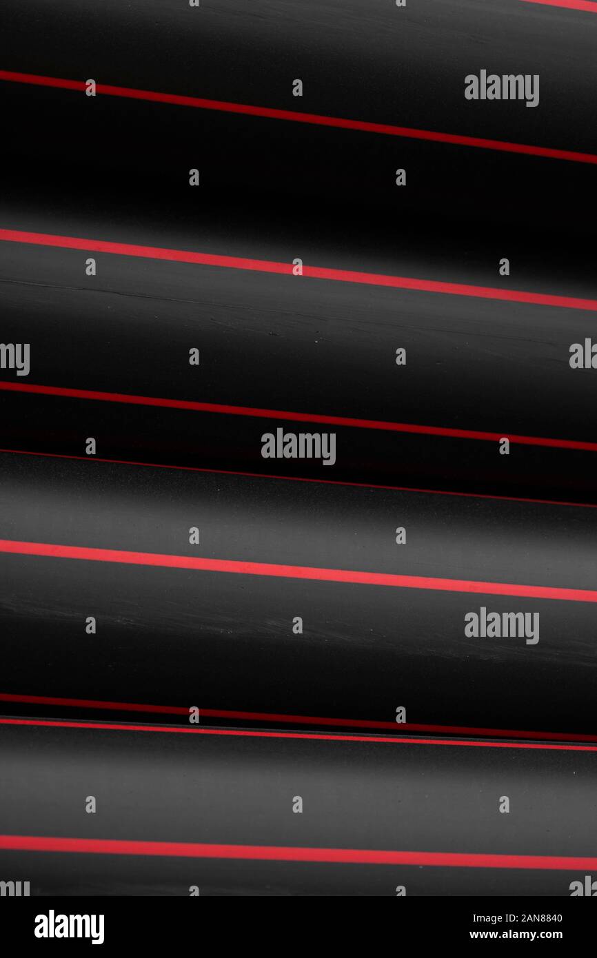 Black rubber or plastic pipes with a red lines as a construction ...