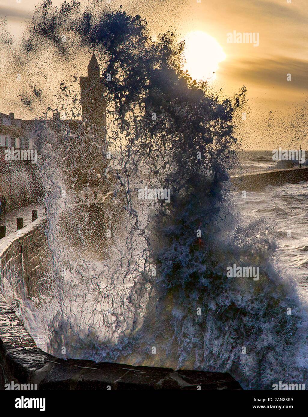 Porthleven Cornwall clock tower,in a storm at sunset,with large waves ...