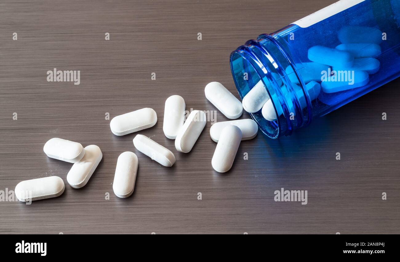 White generic Paracetamol pills spilling out of blue container on ...