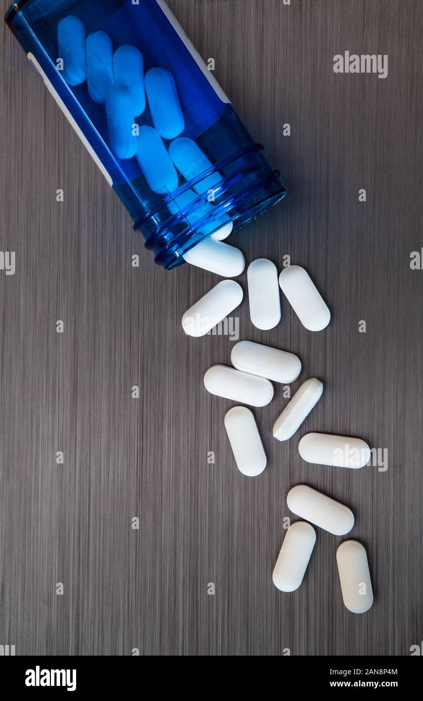 White generic Paracetamol pills spilling out of blue container on ...