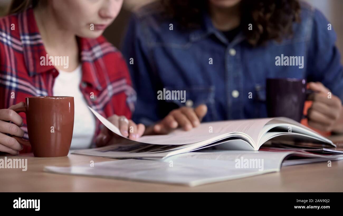 Best friends drinking tea and looking through pictures in magazine ...