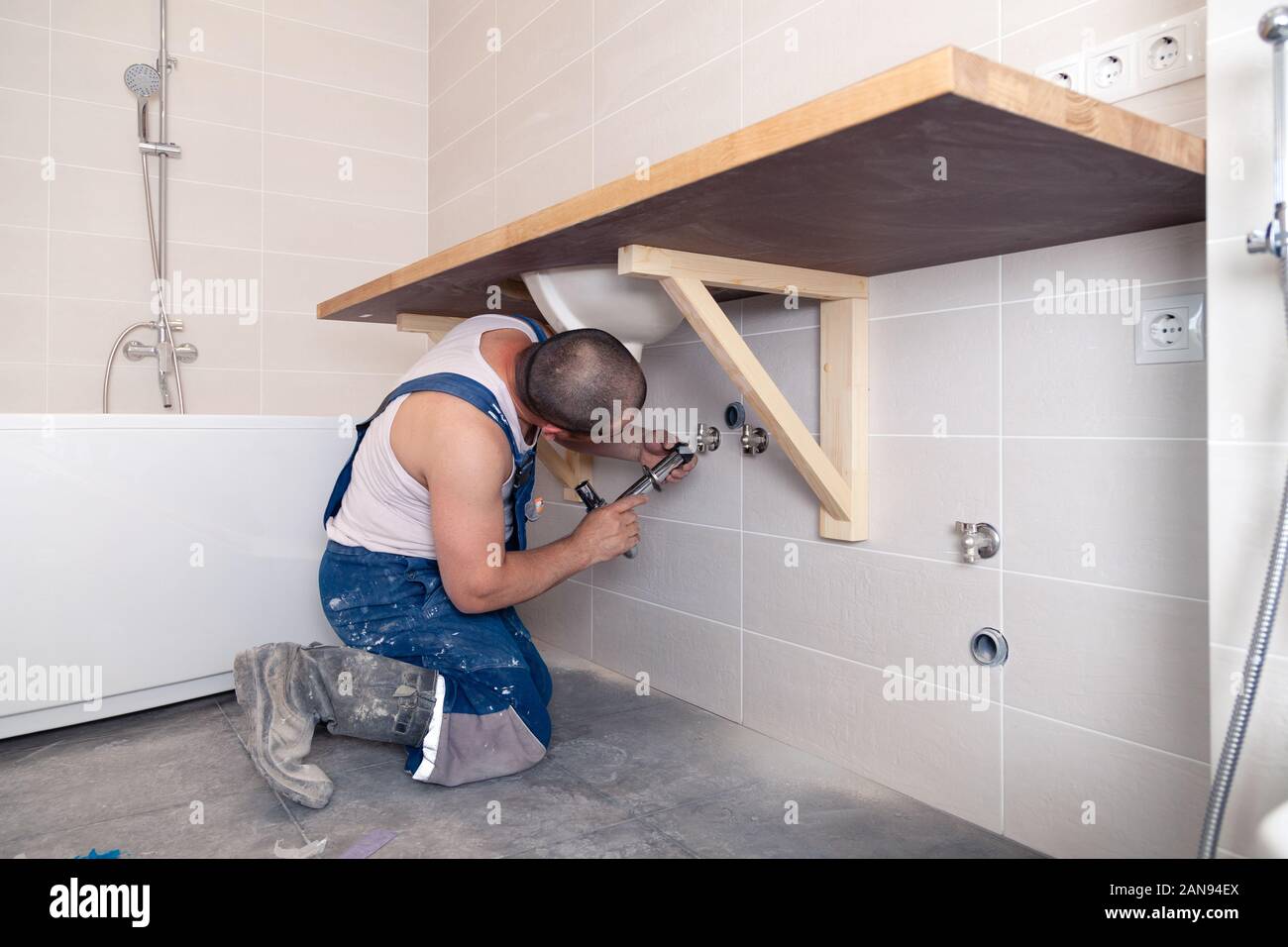 Closeup male plumber worker in blue denim uniform, overalls, fixing ...