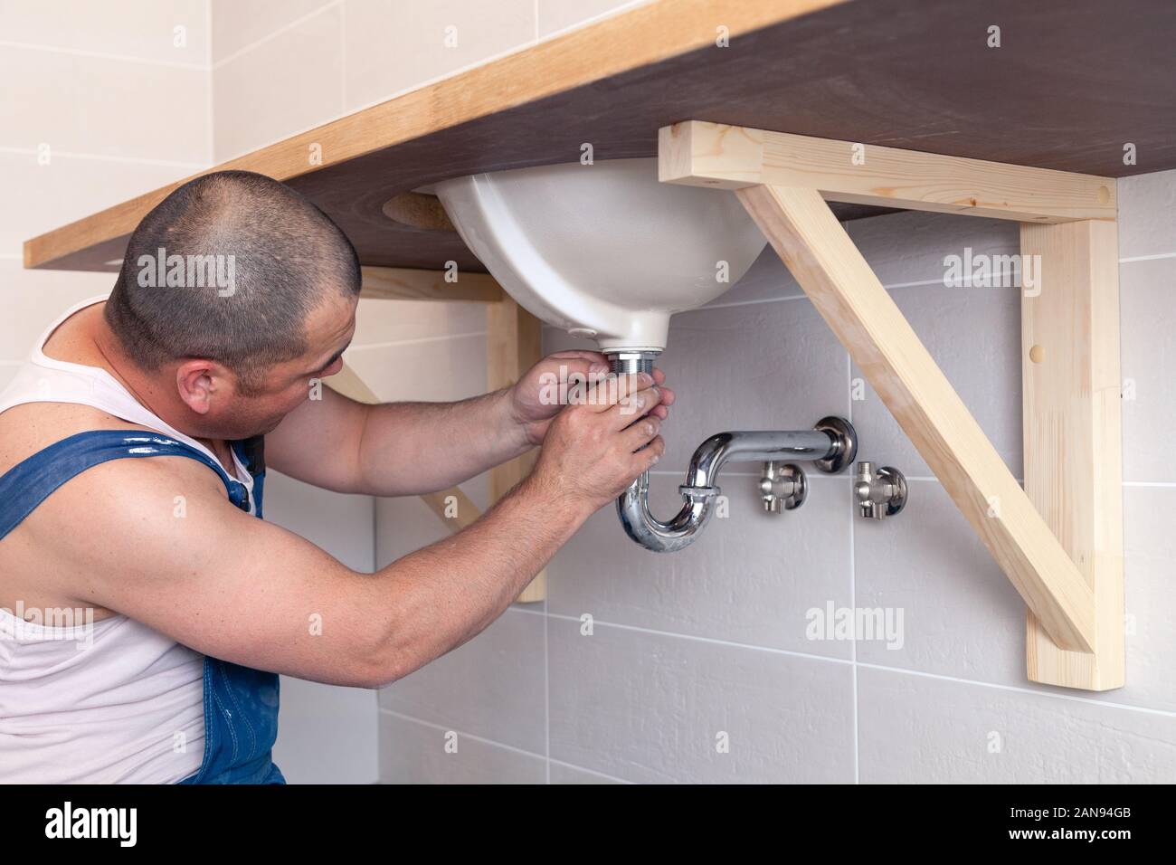 Closeup male plumber worker in blue denim uniform, overalls, fixing ...