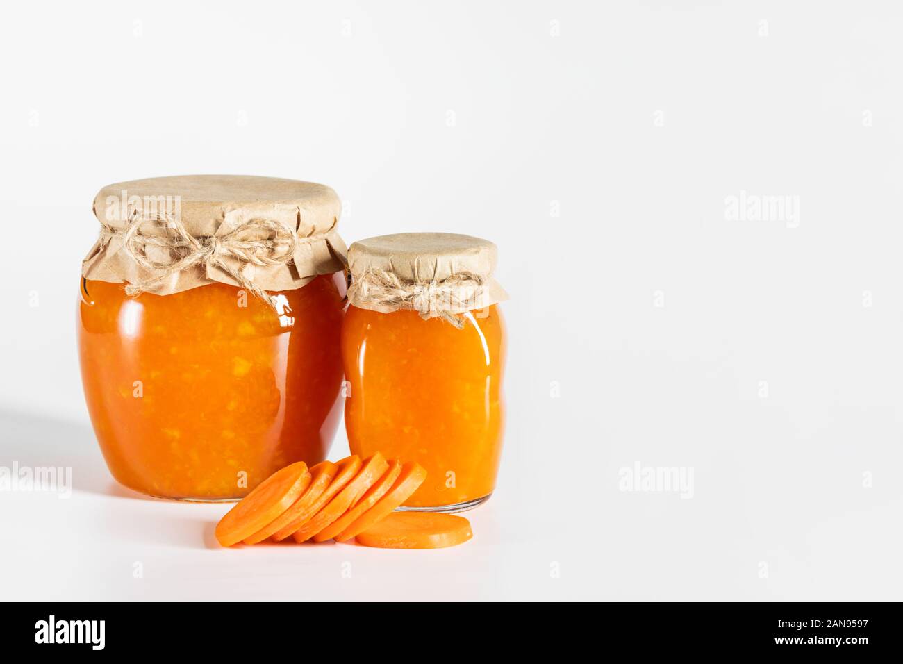 Juicy homemade carrot jam in glass jars on a white background. Side ...