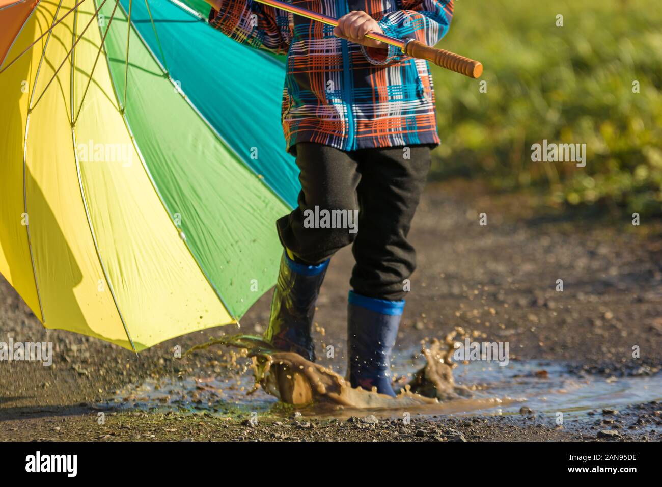Child is playing with colorful umbrella in a puddle Stock Photo - Alamy
