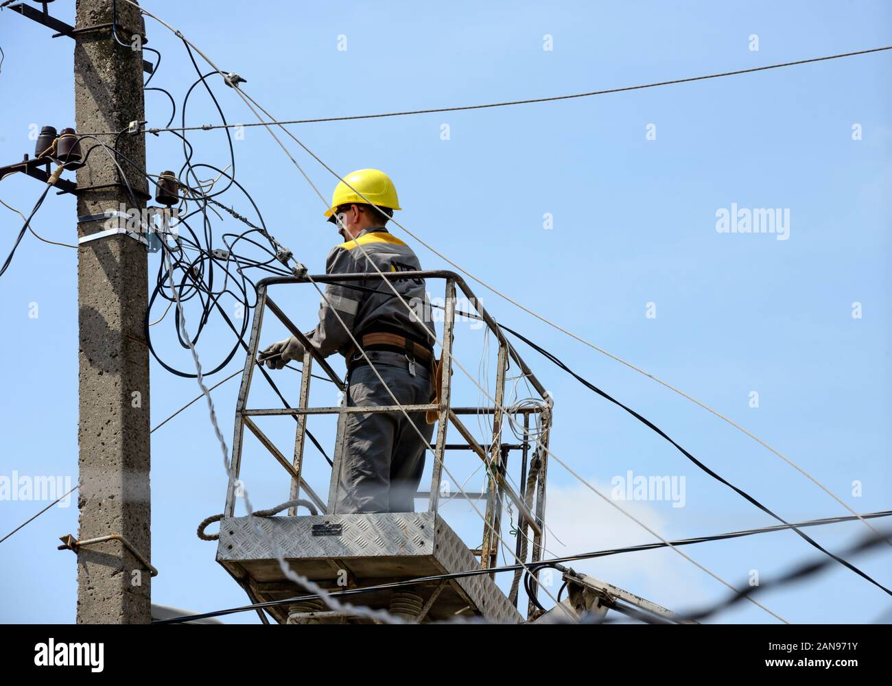 Electrician repairman is working on aerial work platform near top of ...