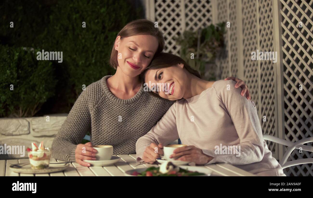 Happy lady hugging best friend, sitting on cafe terrace, having ...