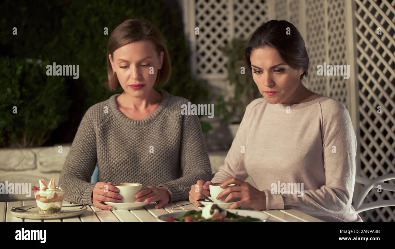 Sad young women thinking of problem sitting in cafe, sisters ...