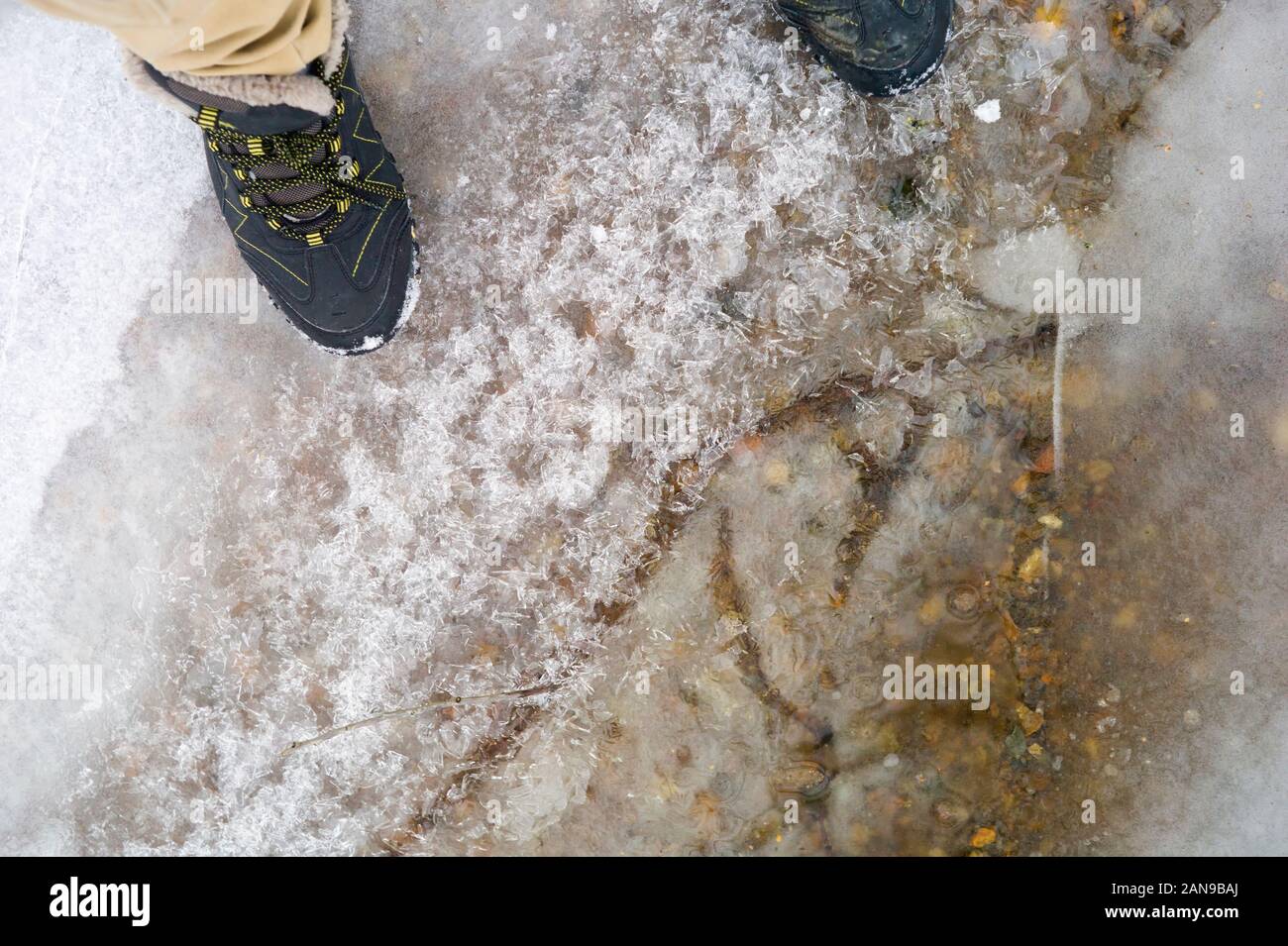 Feet wearing winter boots standing on cracked ice, concept of danger ...