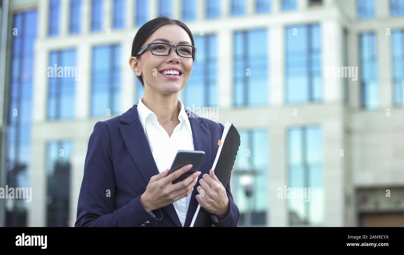 Happy female employee holding smartphone, satisfied good news, business ...