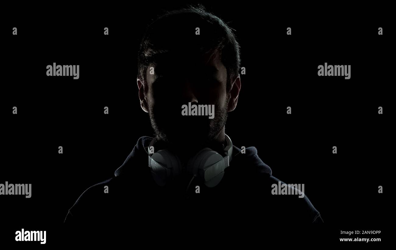 Silhouette of young man in headphones on black background, millennial ...