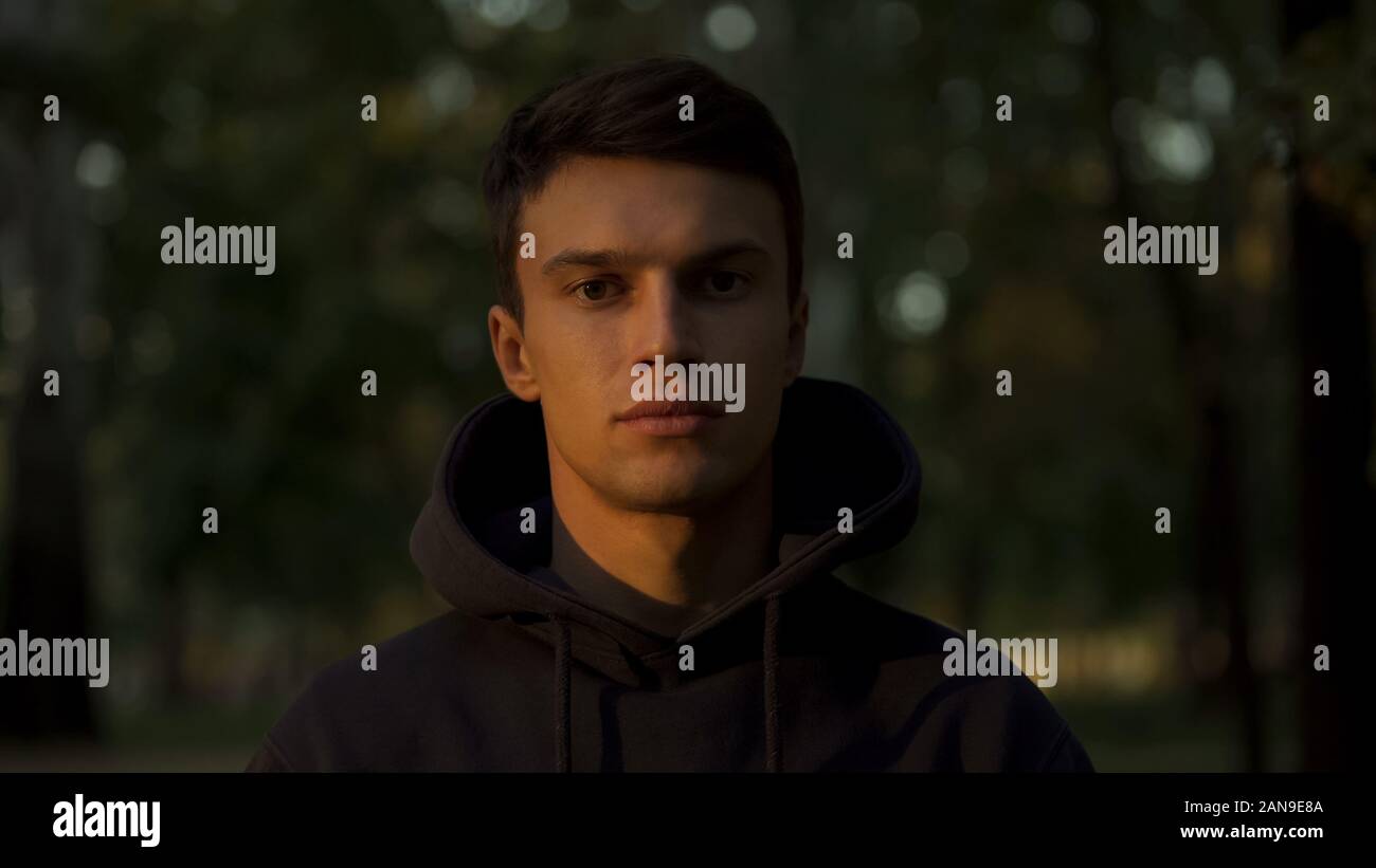 Young man looking at camera, half shadowed face, good and evil fight ...