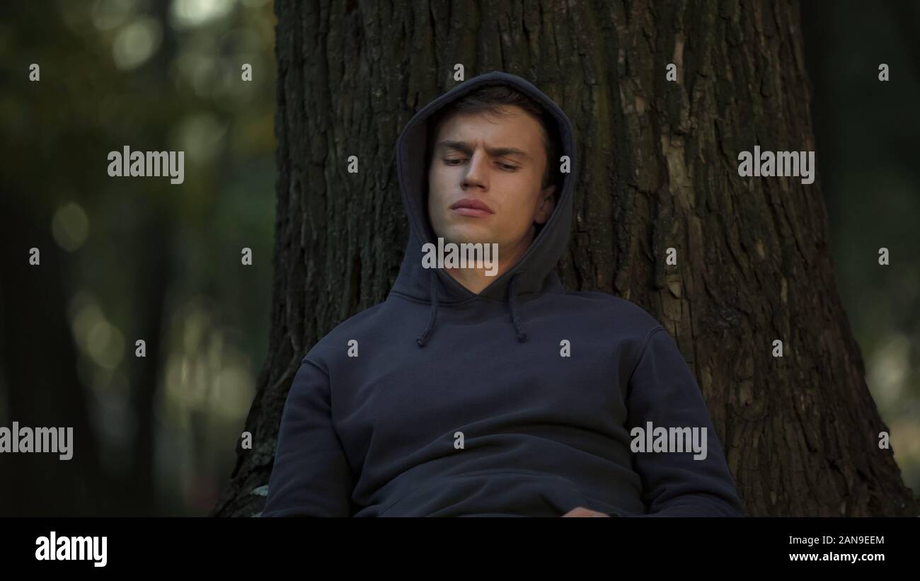 Sad man sitting under tree in park, feeling depression and insecurities ...