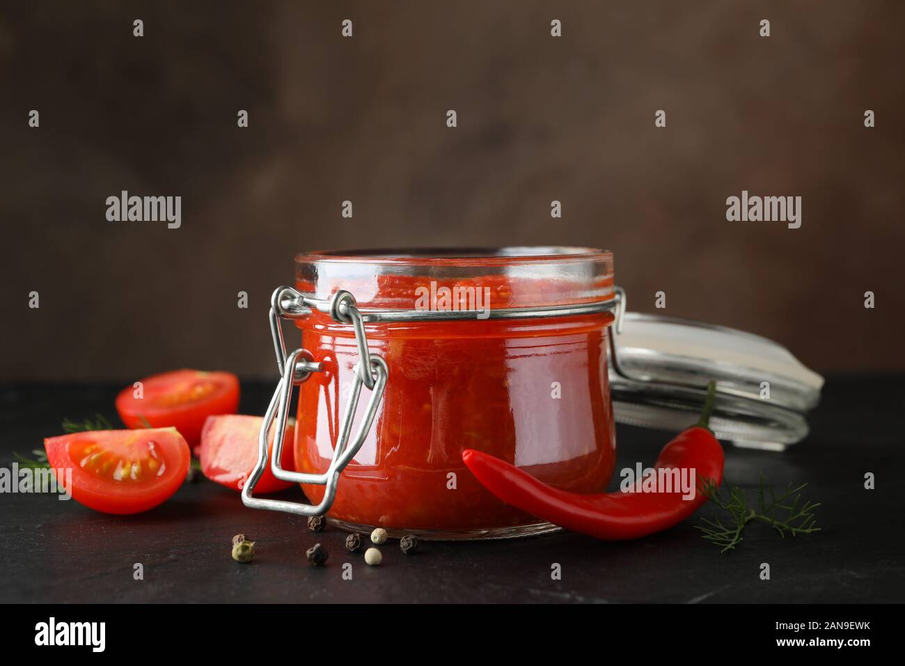Bowl of chilli sauce, ingredients on black background, space for text ...
