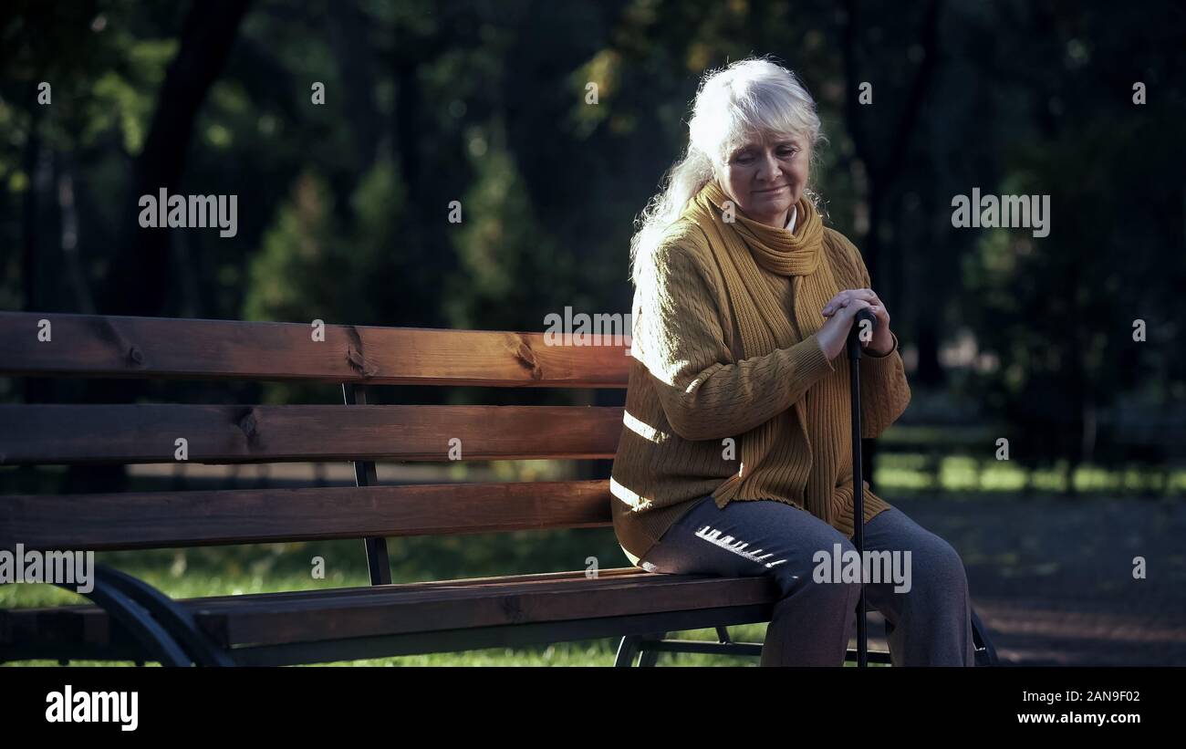 Sad lonely old woman sitting on bench in park, abandoned elderly people ...