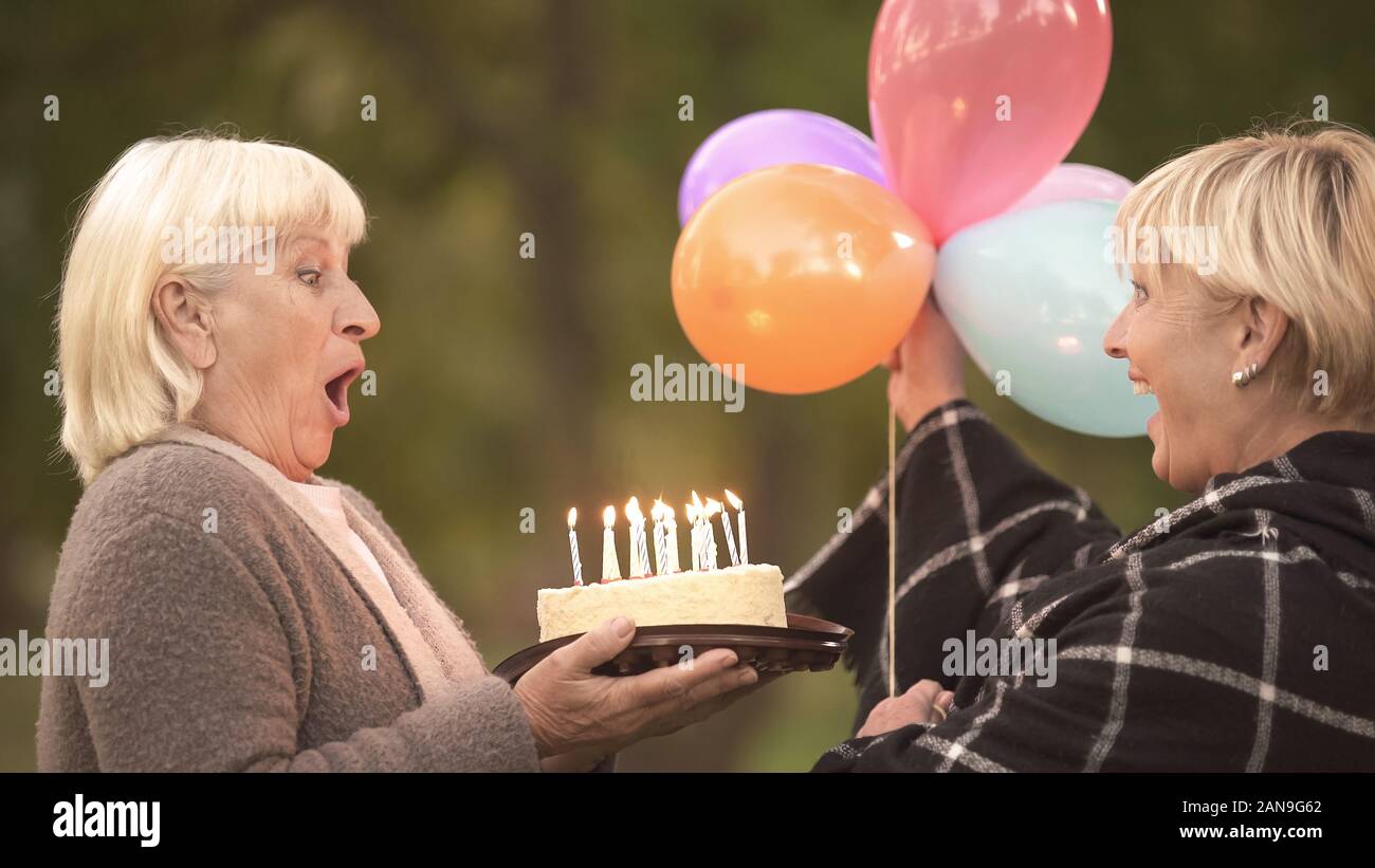 Mature Woman Going To Blow Out Candles On Birthday Cake From Best